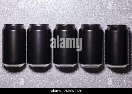 Photo of five black blank aluminium cans in a row with hard lighting on ...