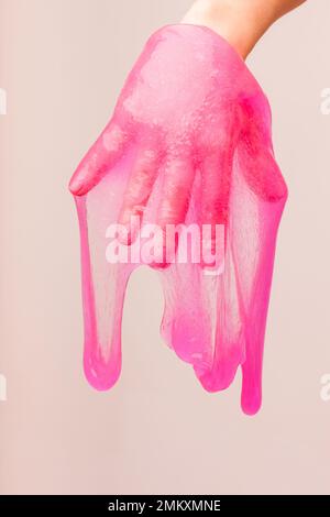 a toy for children mucus and liquid flowing on hand on a white ...