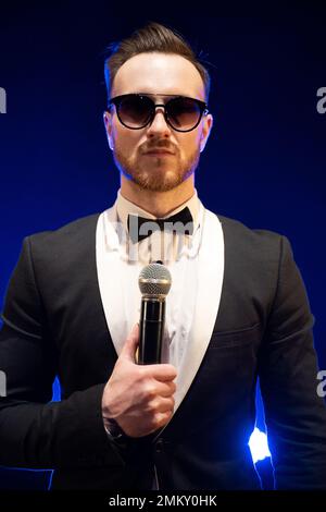 handsome presenter and showman in a stylish suit with a microphone on ...