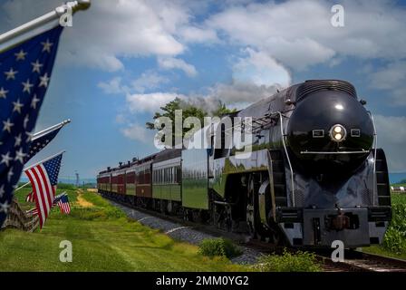 A Restored Steam Passenger Train Approaches As American Flags Wave on a ...