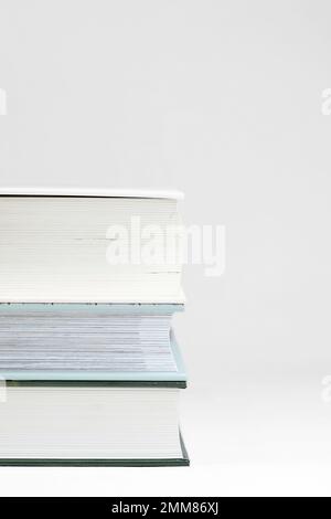 Three thick books on a table with a white background Stock Photo - Alamy