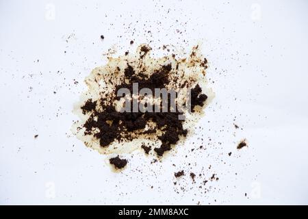 spilled coffee grounds on a white background and a teaspoon lies next ...