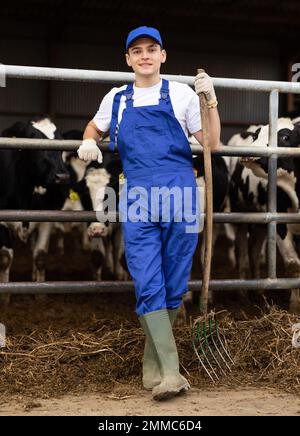 Hardworking young guy farmer in overalls collecting buckets of water ...