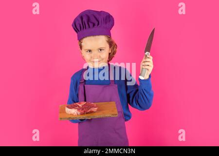 Child cook hold cutting board with meat beef steak and knife. Teen boy ...