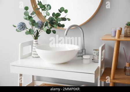 Sink, vase with flowers and eucalyptus on table in bathroom Stock Photo ...