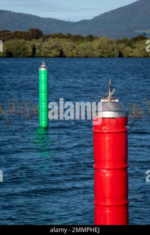 Red and green navigation markers either side of boating channel leading ...