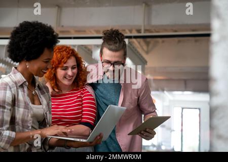 Smiling group of diverse businesspeople going over paperwork together ...