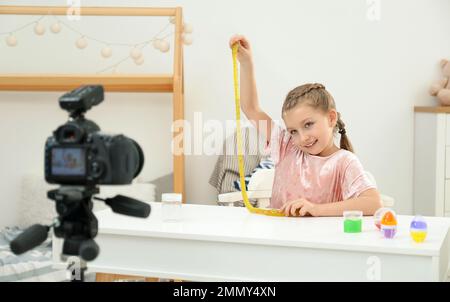 Cute little blogger with slime recording video at home, focus on camera ...