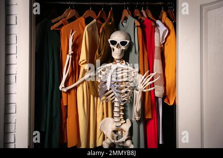 Artificial human skeleton model among clothes in wardrobe Stock Photo ...