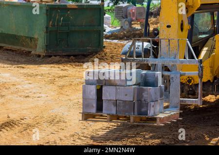 Forklift with boom truck moving cement blocks to place where wall of ...