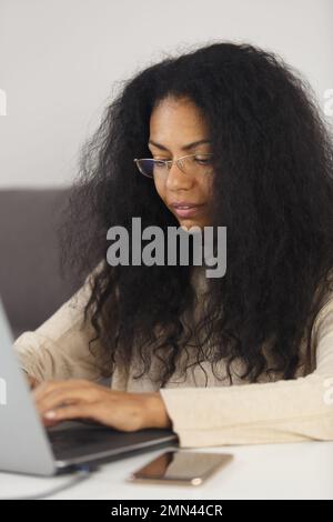 BIPOC woman works on computer in an office. Black female clicking with ...