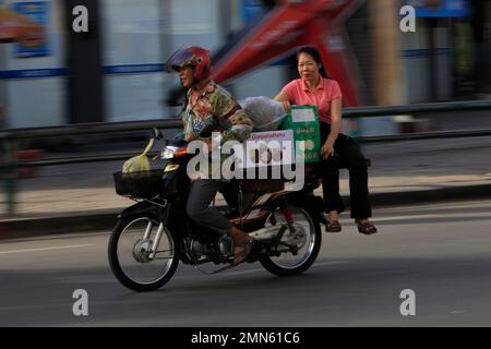 A Cambodian motor-taxi driver carries his customer and her goods to the ...