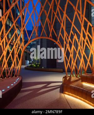 Wooden pavilion illuminated and glowing up against an office building ...