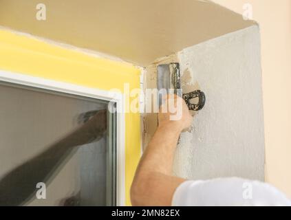Man plastering window area with putty knife indoors, closeup. Interior ...