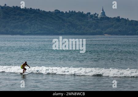 Male surfing in distance in Unawatuwa, Galle sea riding moderate wave ...