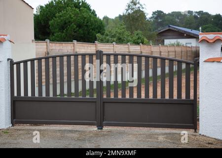 Gray metal driveway entrance gates set in brick fence with lock Stock ...