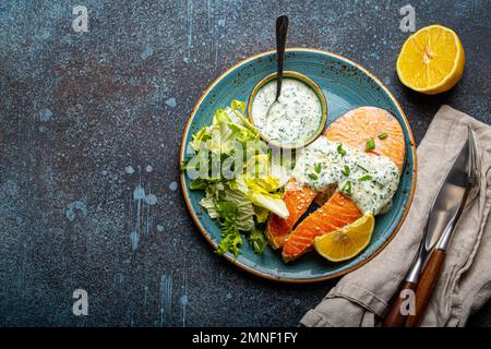 Flat lay. Grilled salmon steaks garnished with green onions on a black ...