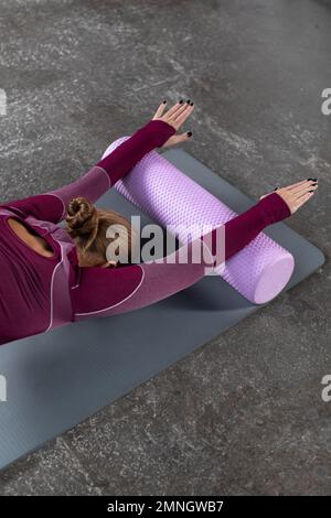 A fitness instructor demonstrates myofascial release using a roller to ...
