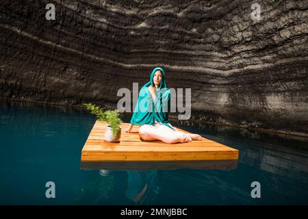 Woman sitting on wooden raft in cenote Stock Photo - Alamy