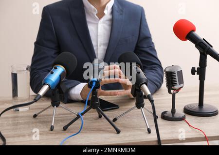 Businessman giving interview at table with microphones, closeup ...