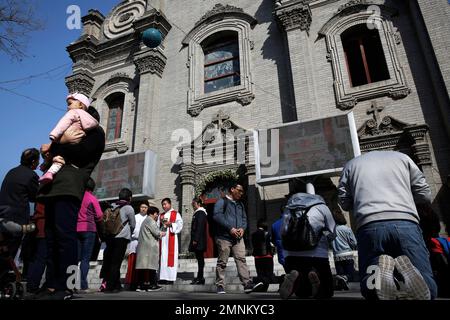 Chinese Catholics line up to receive bread from a priest outside the ...