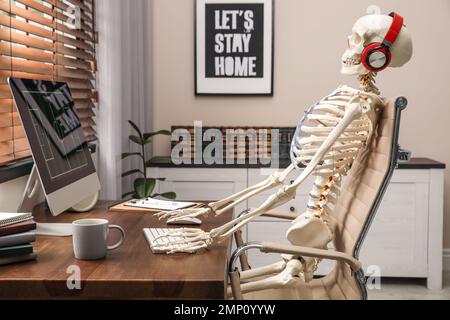 Human skeleton with headphones using computer at workplace Stock Photo ...