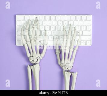 Human skeleton using computer keyboard on red background, top view ...