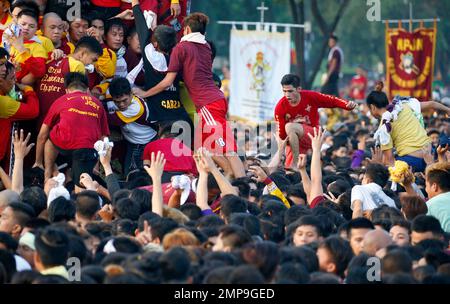 Filipino Roman Catholic devotees jostle to kiss and rub with towels the ...