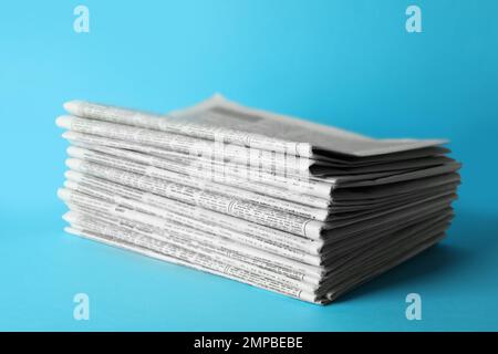 Stack of newspapers on light blue background. Journalist's work Stock ...