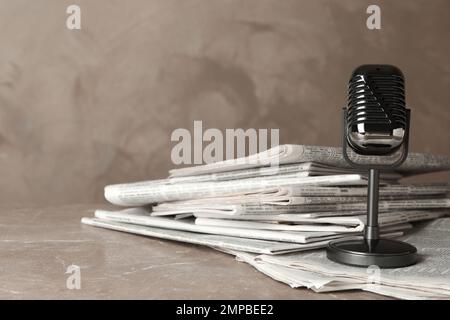 Newspapers and vintage microphone on marble table. Journalist's work ...