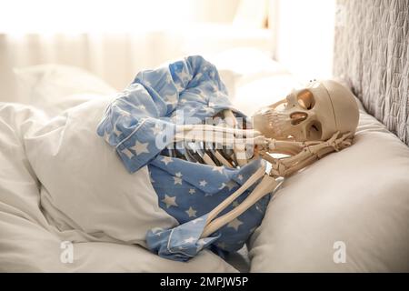 Human skeleton in pajamas lying on bed indoors Stock Photo - Alamy