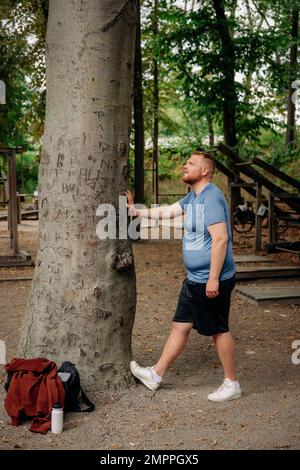 Side view of man stretching on wooden walkway by river against sky ...