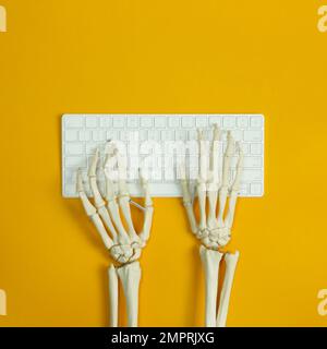 Human skeleton using computer keyboard at grey marble table, top view ...