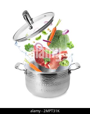 Many different ingredients falling into pot on white background ...