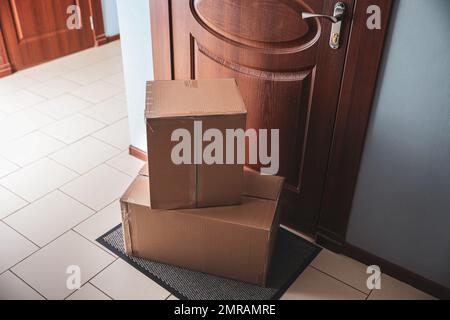 Cardboard boxes on rug near door. Parcel delivery service Stock Photo ...