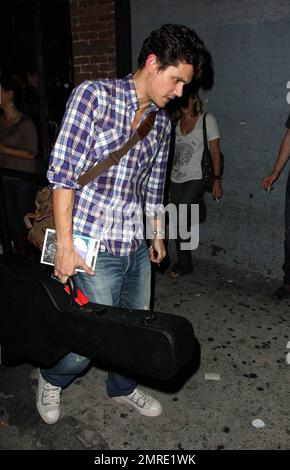 Musician John Mayer signs a guitar for a fan as he leaves the Hotel ...