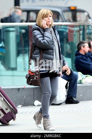 Packages in hand, GMTV presenter Kate Garraway chats on her cellphone ...