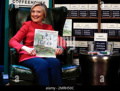 Hillary Clinton holds her book "It Takes A Village" as she sits on ...