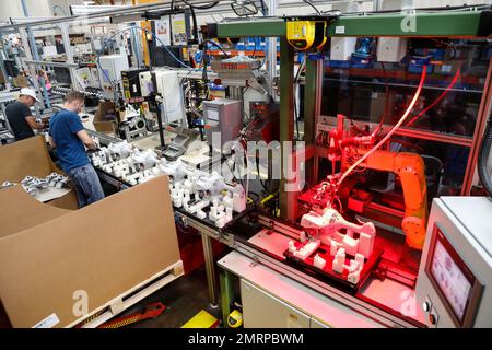 A collaborative robot works alongside manufacturing laborers on a ...