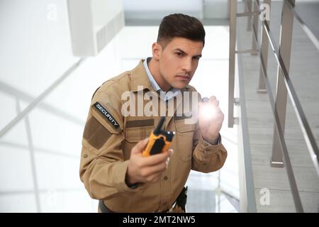 Professional security guard with flashlight and portable radio set on ...