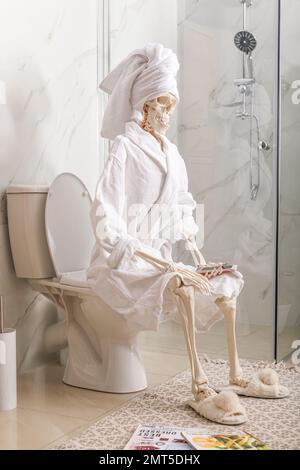 Skeleton in bathrobe sitting on toilet bowl Stock Photo - Alamy