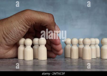 Hand separate group of wooden dolls. Mass layoffs, downsizing concept ...