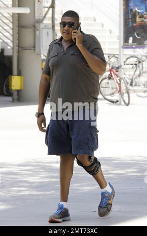 Wearing a knee brace, actor Omar Benson Miller chats on his cellphone ...