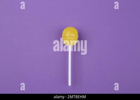 Tasty lemon lollipop on purple background, top view. Space for text ...