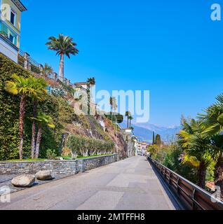 Panorama of embankment of Lake Maggiore with green park, moored ferry ...
