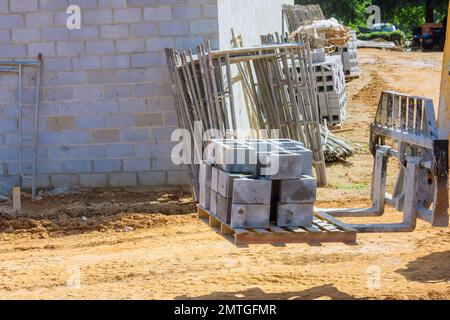 Boom forklift moving cement blocks to place of installation of wall of ...