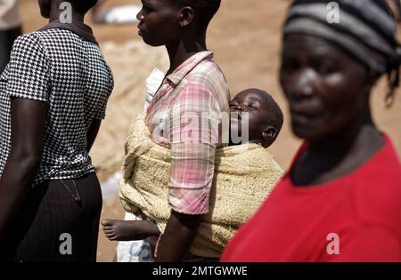A South Sudanese refugee baby sleeps on his mother's back as she ...
