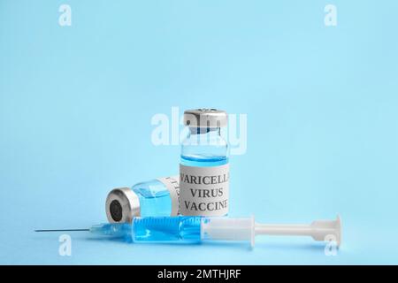 Chickenpox vaccine and syringe on light blue background, space for text ...