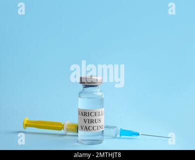 Chickenpox vaccine and syringe on light blue background, space for text ...