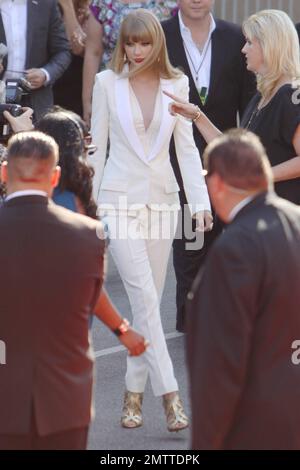 Wearing a white pant suit with tan high heels, singer Taylor Swift ...